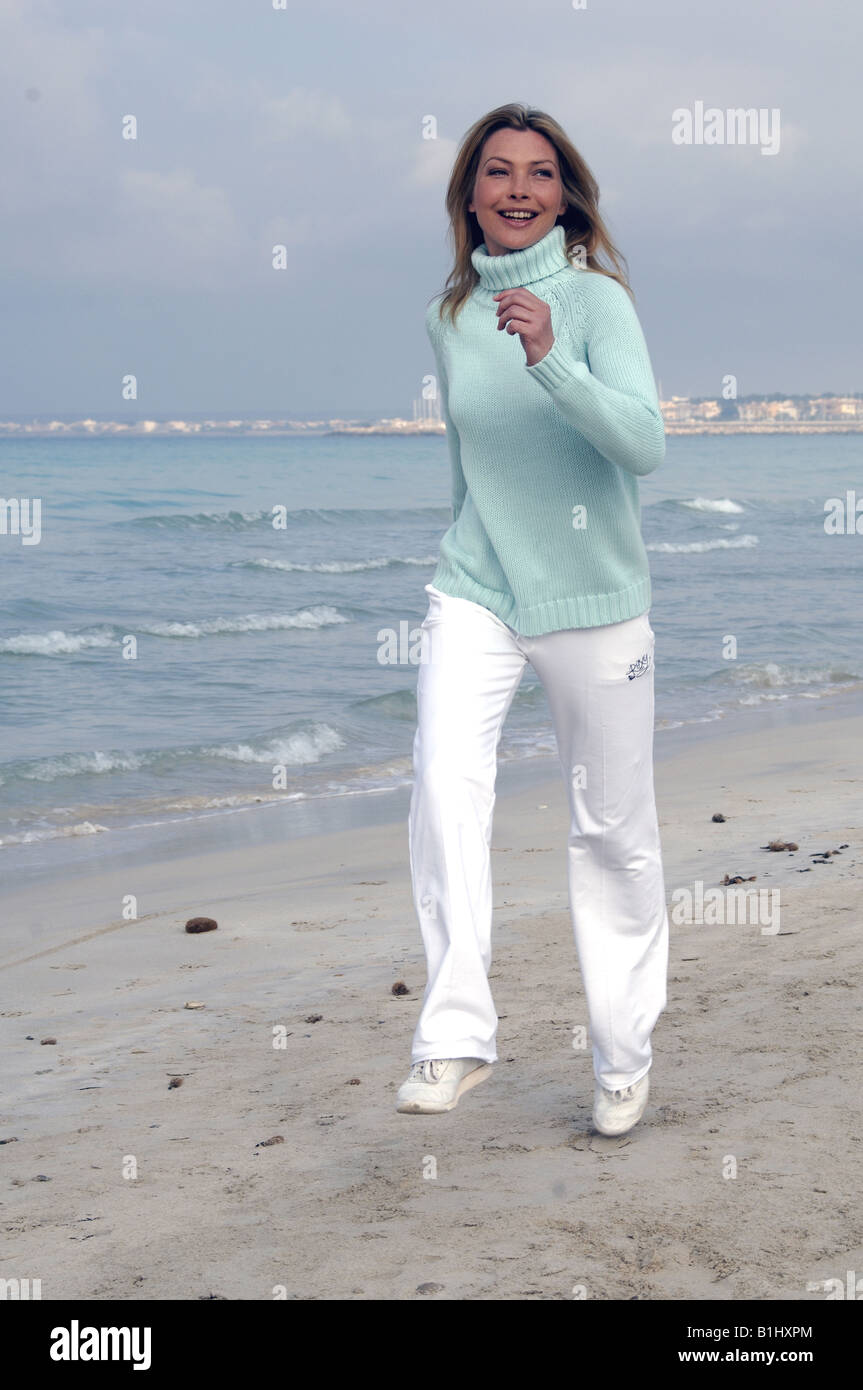 Running woman in turquoise pullover at the sea Stock Photo - Alamy