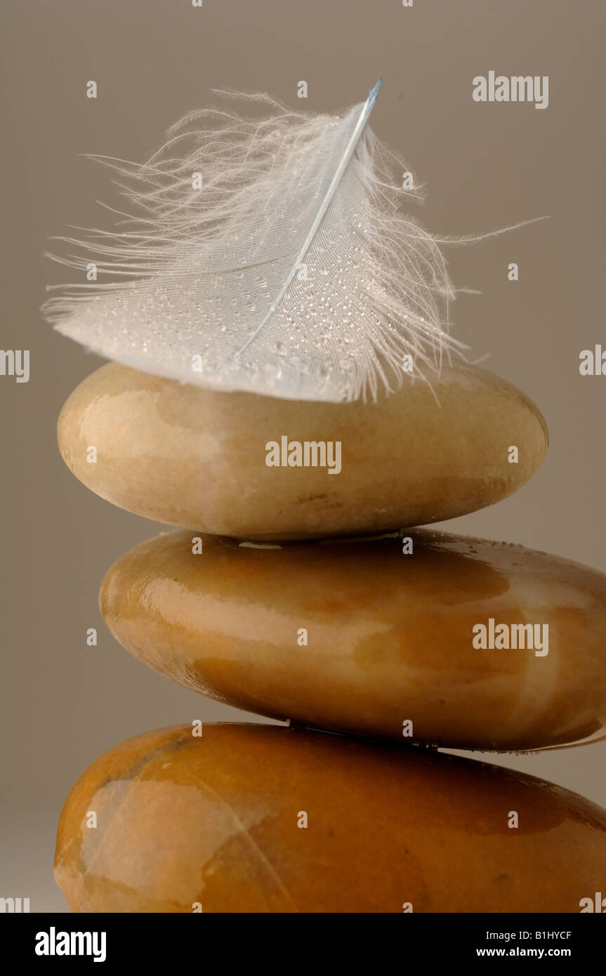Stacked stones with a feather Stock Photo - Alamy