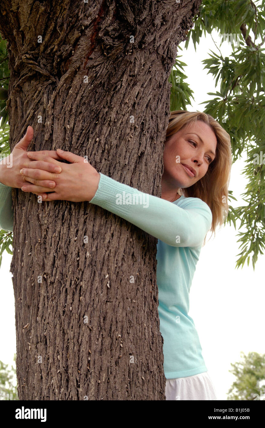 Woman embraces a tree in a meadow Stock Photo - Alamy