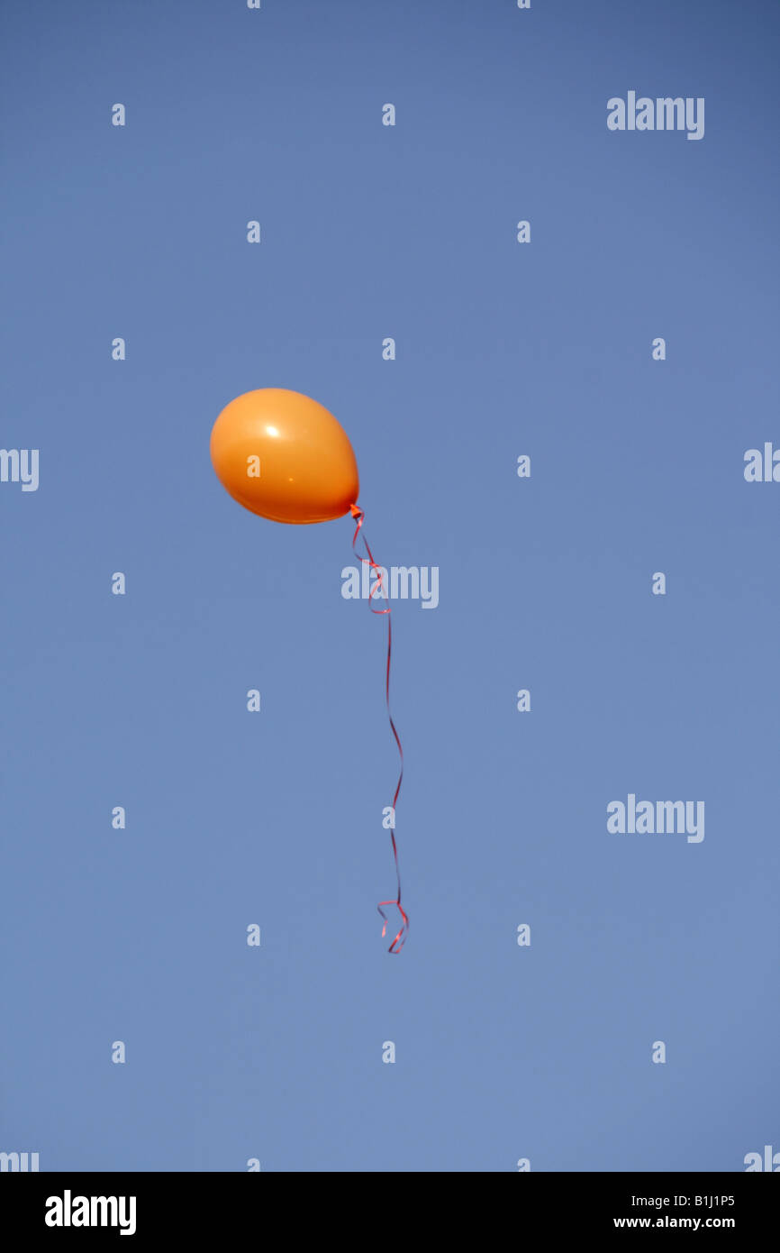 one single orange balloon floating in blue sky Stock Photo - Alamy