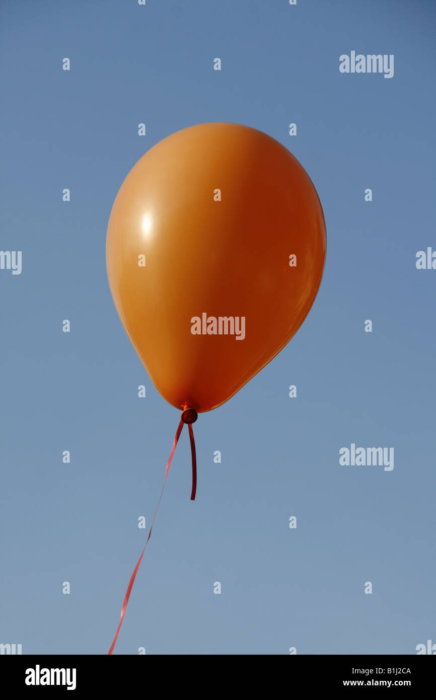 one single orange balloon floating in blue sky Stock Photo - Alamy
