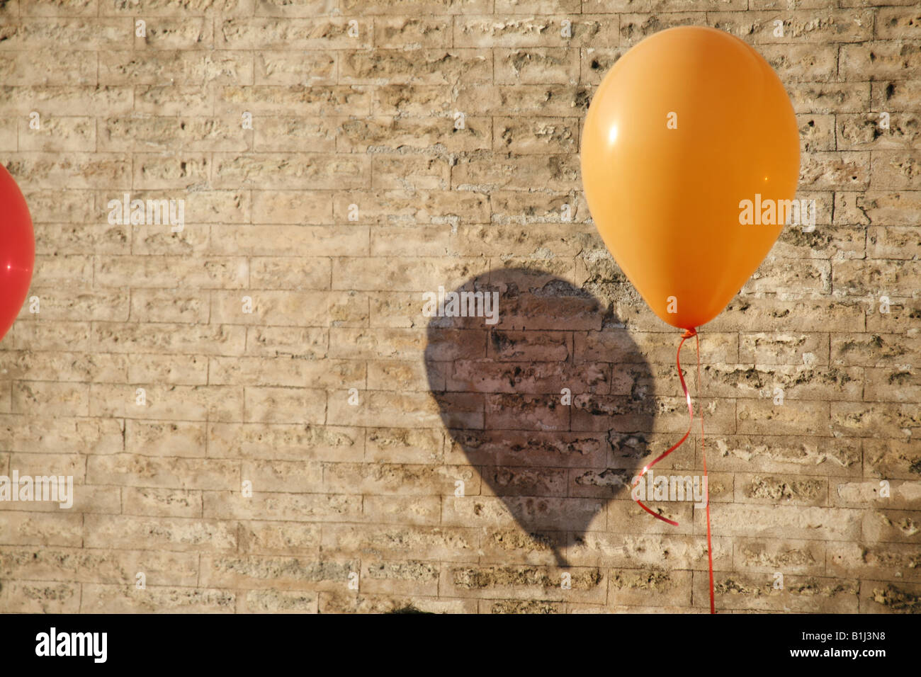 one orange balloon floating against wall Stock Photo - Alamy
