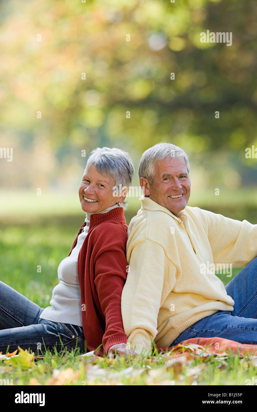 Senior couple sitting back to back in a park Stock Photo - Alamy