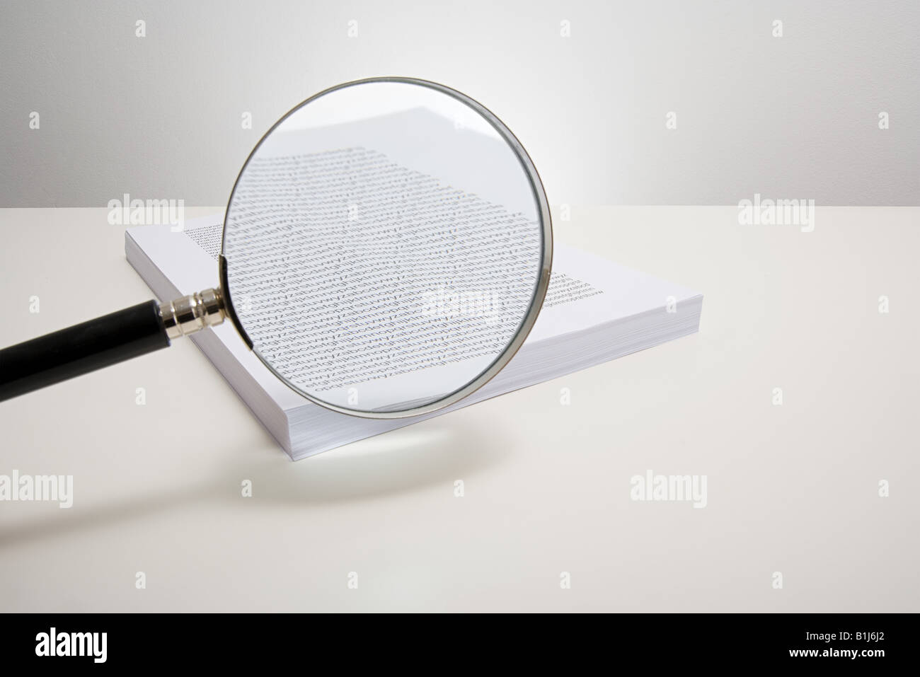 Magnifying glass and a stack of paper Stock Photo - Alamy
