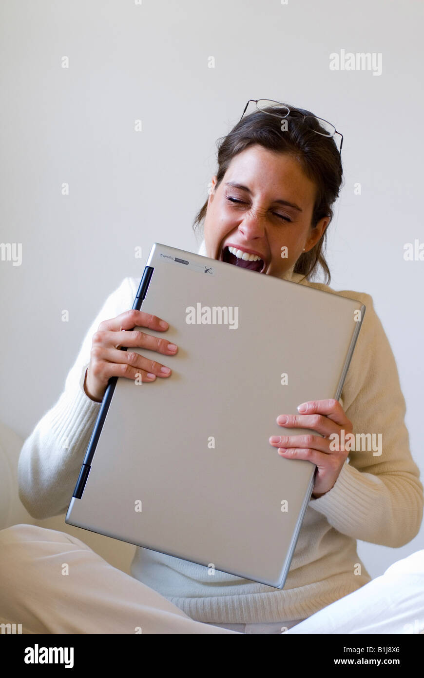 young woman biting on her laptop in frustration Stock Photo - Alamy