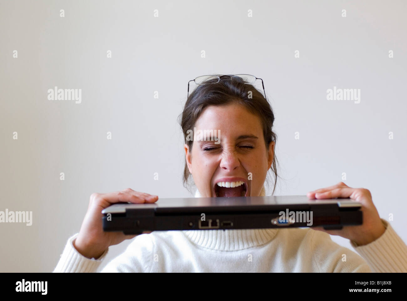 young woman biting on her laptop in frustration Stock Photo - Alamy