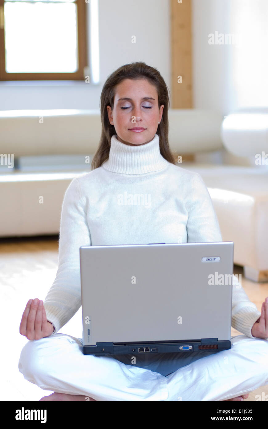 young attractive woman practising yoga with a notebook on her lap ...
