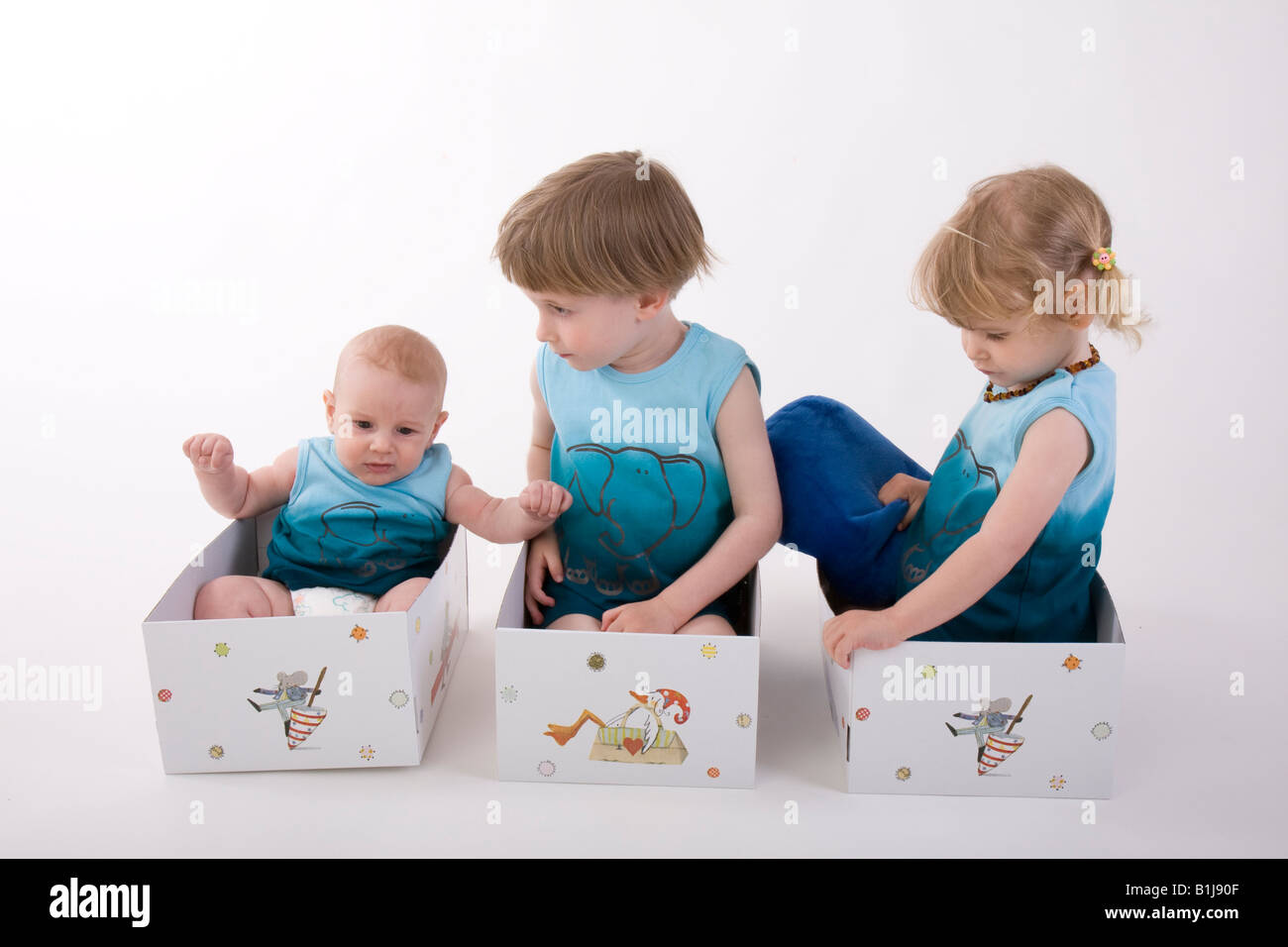 three little children sitting in boxes Stock Photo - Alamy