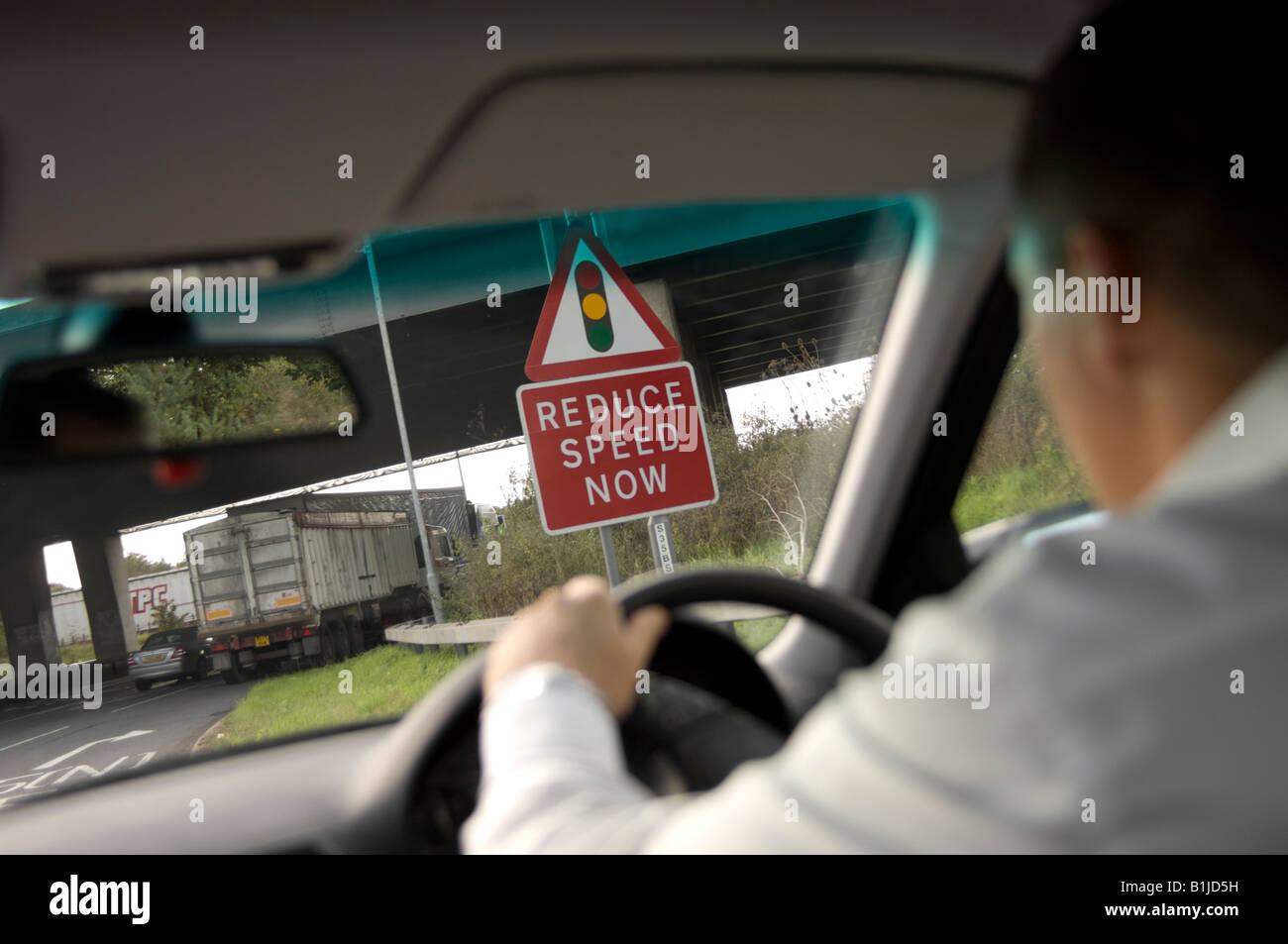 Driving a car past a Reduce Speed sign Stock Photo - Alamy