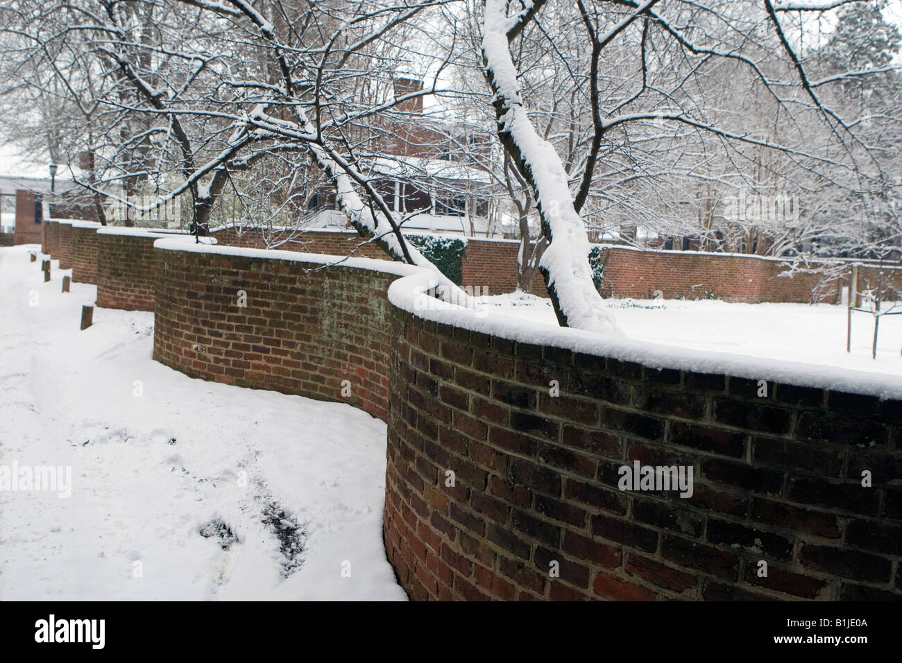 A serpentine brick wall is covered by snow during a winter storm on the ...