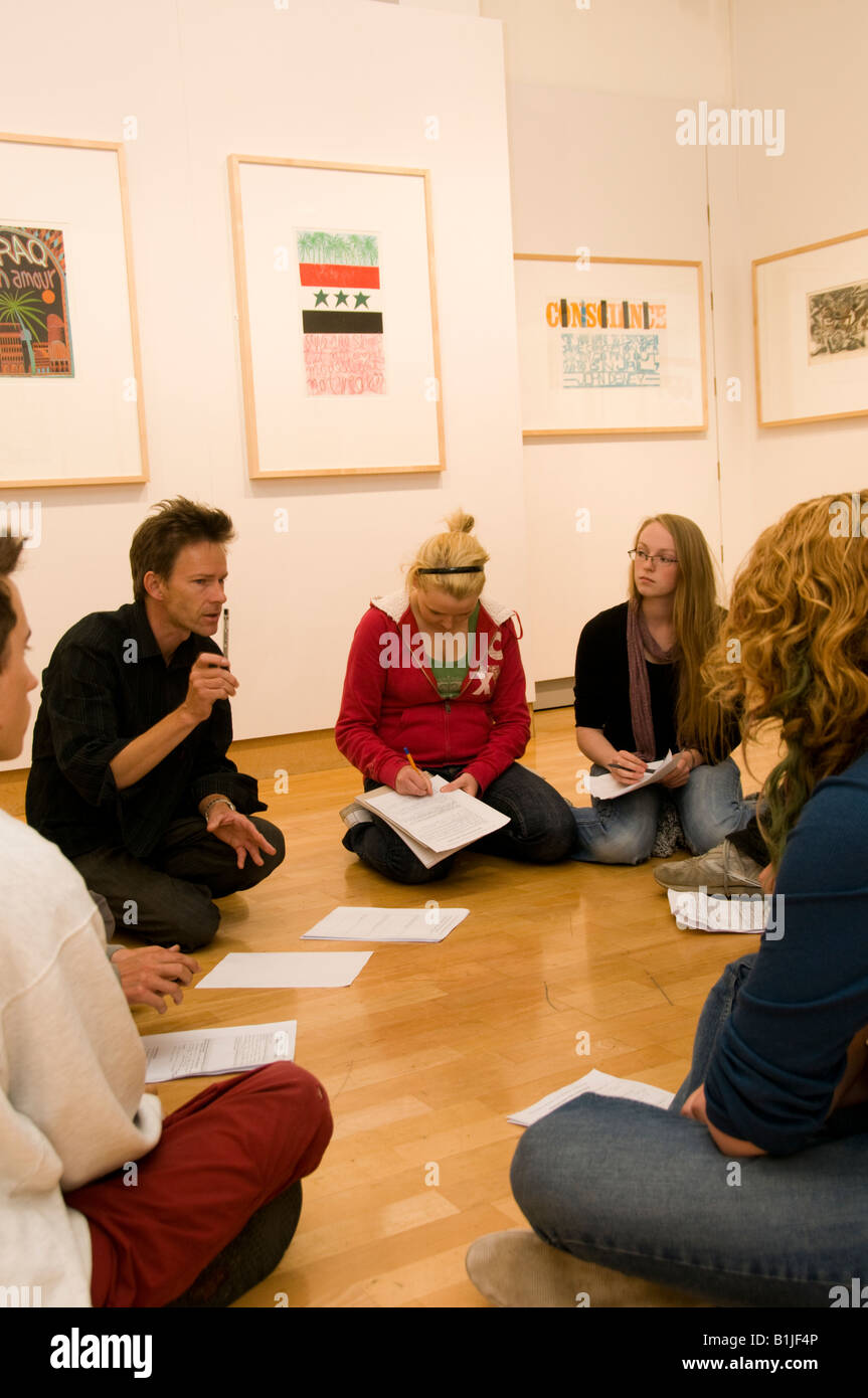 A Level Visual Art teenage students discussing with tutor an exhibition ...