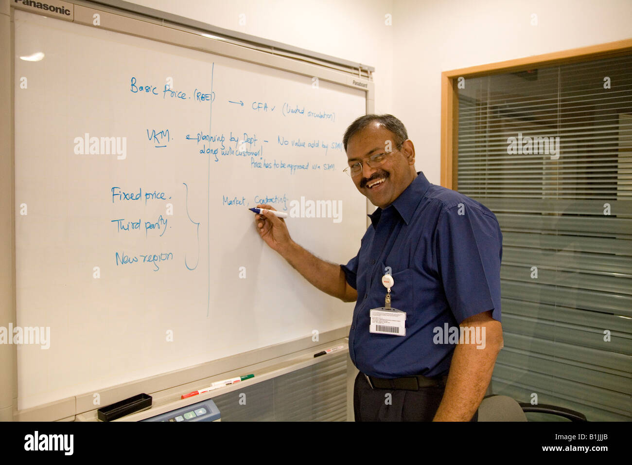 A senior manager gives a presentation on a whiteboard in an office in ...