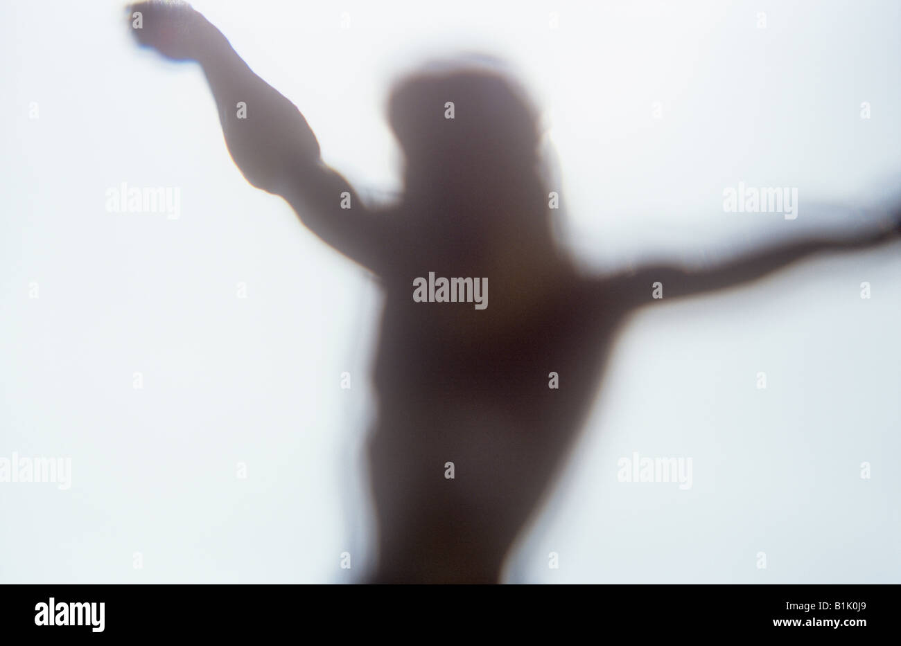 Impressionistic shadowy figure with arms raised and splayed and moving ...