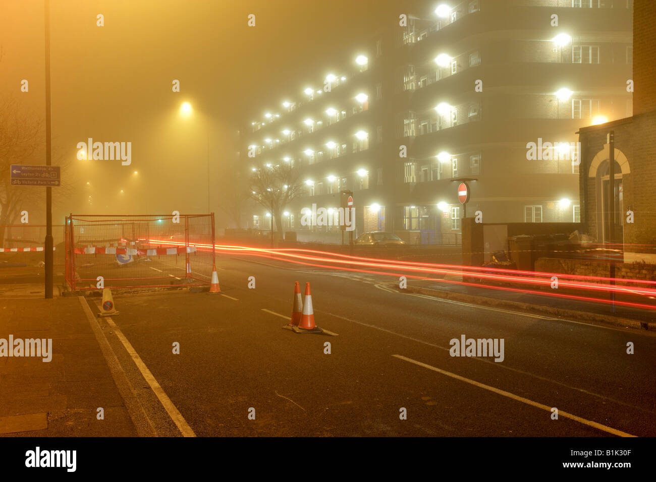 night time road works tower block flats fog car streamers london united ...