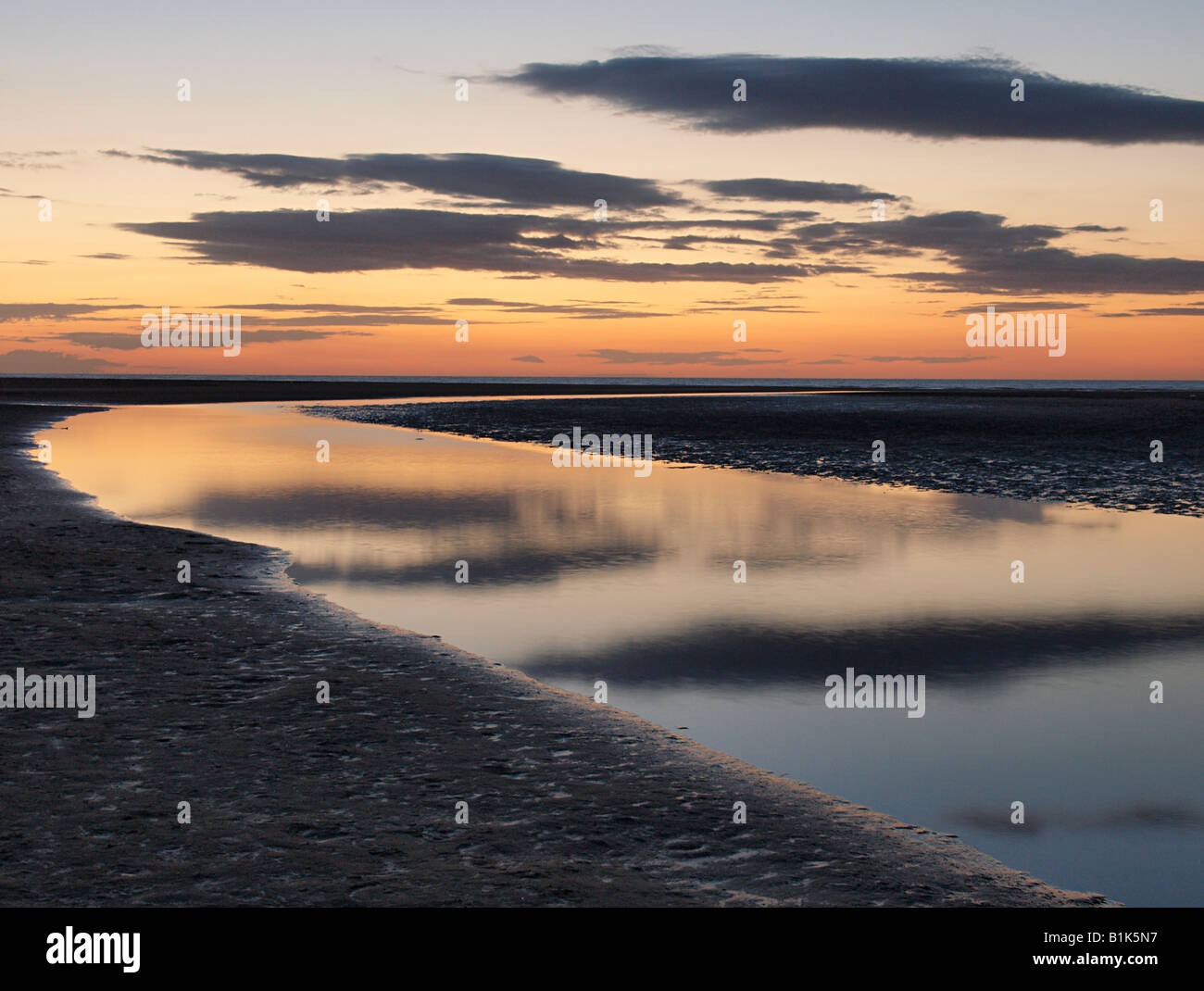 REFLECTION OF CLOUDS AT SUNSET IN CHANNEL OF SALT WATER LEADING TO SEA ...