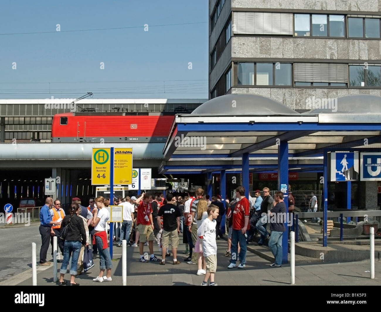 crowd of people at a bus stop waiting for bus in front of the main ...