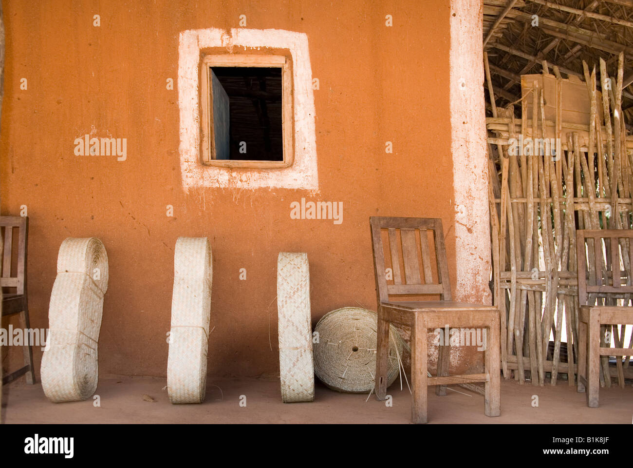 Terra cotta coloured still life under a verandah of a thatched hut ...
