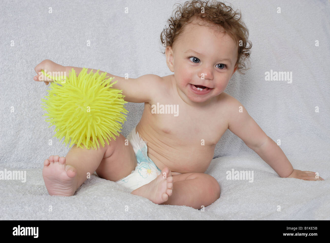 portrait little baby in nappy playing with yellow rubbery toy Stock ...