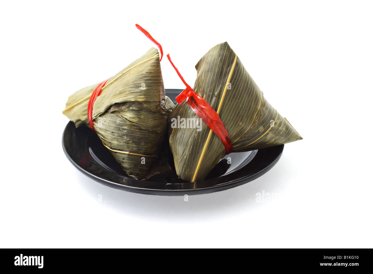 Two wrapped Chinese rice dumplings on plate Stock Photo - Alamy