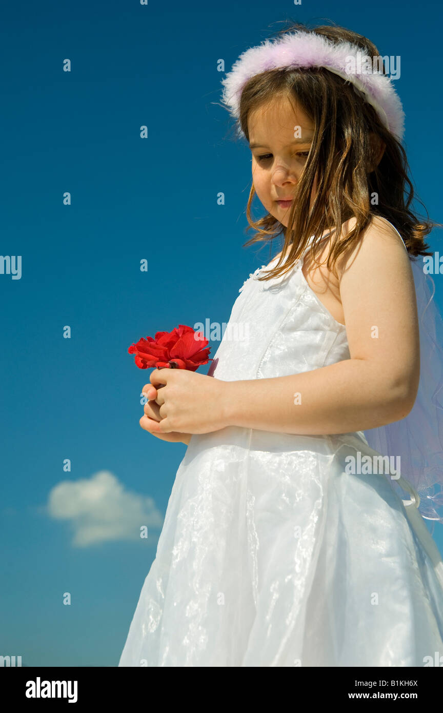 little girl holding red roses against blue sky and a cluod Stock Photo ...