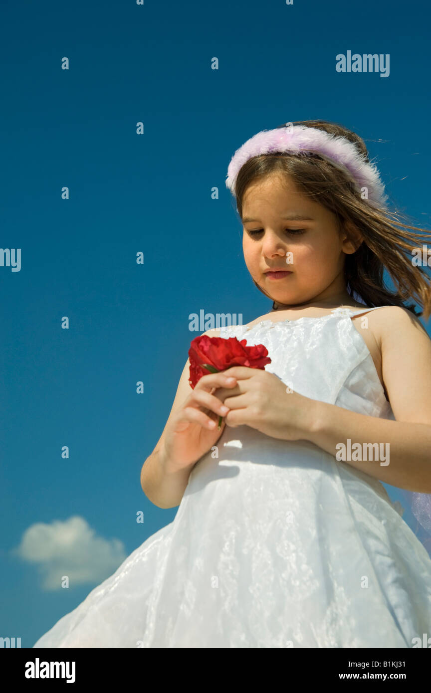 little girl holding red roses against blue sky and a cluod Stock Photo ...