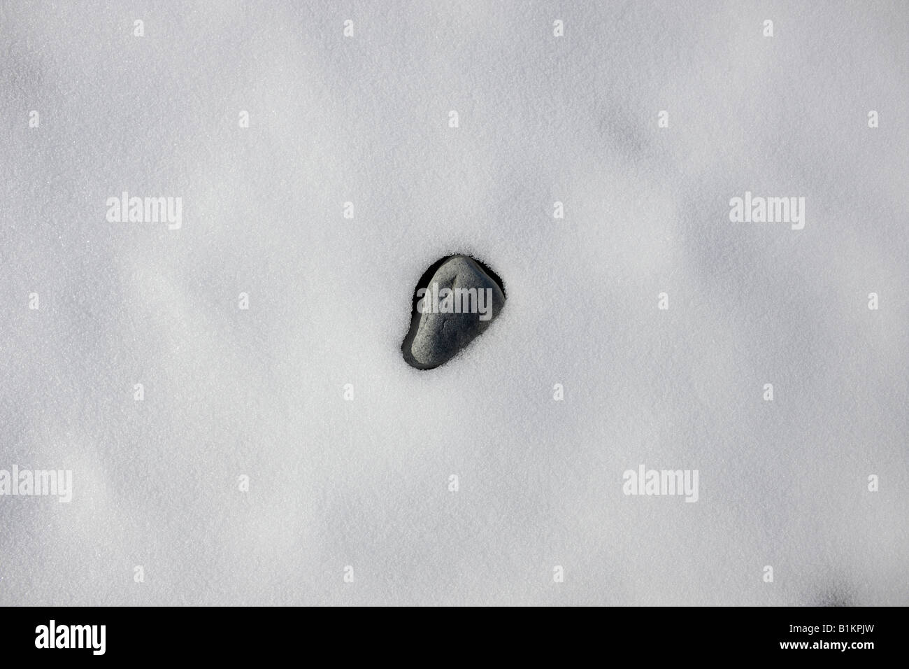 Melting snow and one stone Stock Photo - Alamy