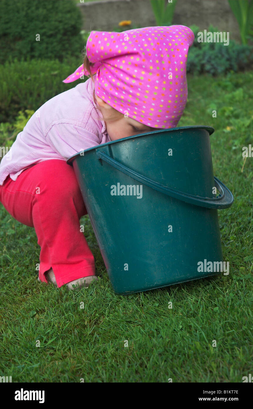 Toddler playing with bucket in yard Stock Photo - Alamy