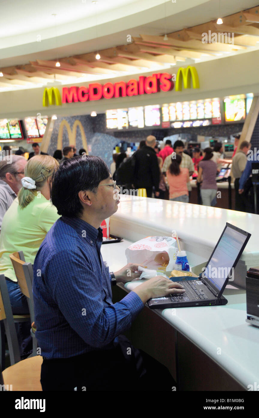 Ethnic Passanger works on laptop computer at Fast food court at Orlando ...