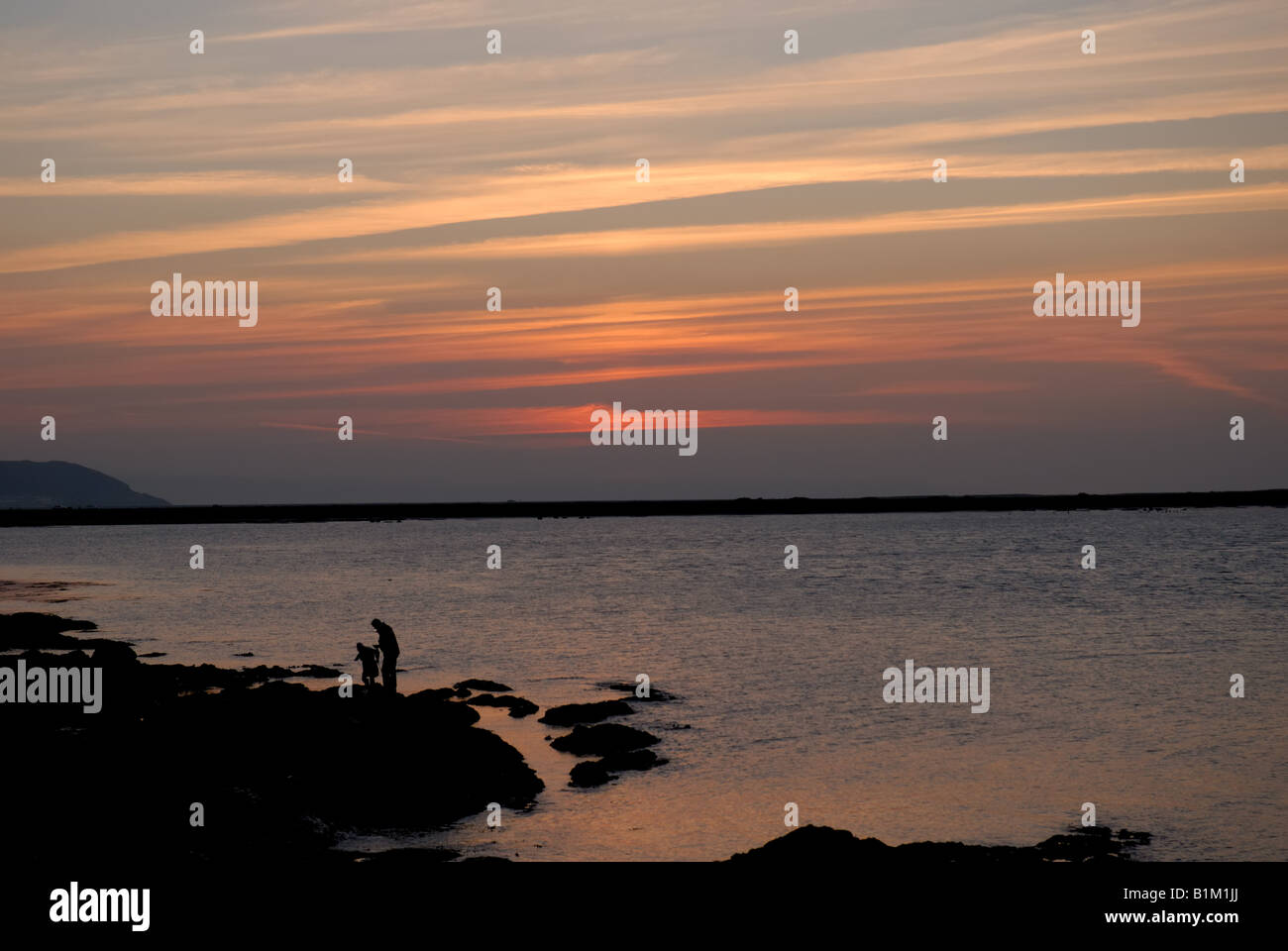 Two figures in silhouette on Appledore beach with sea and sunset Devon ...