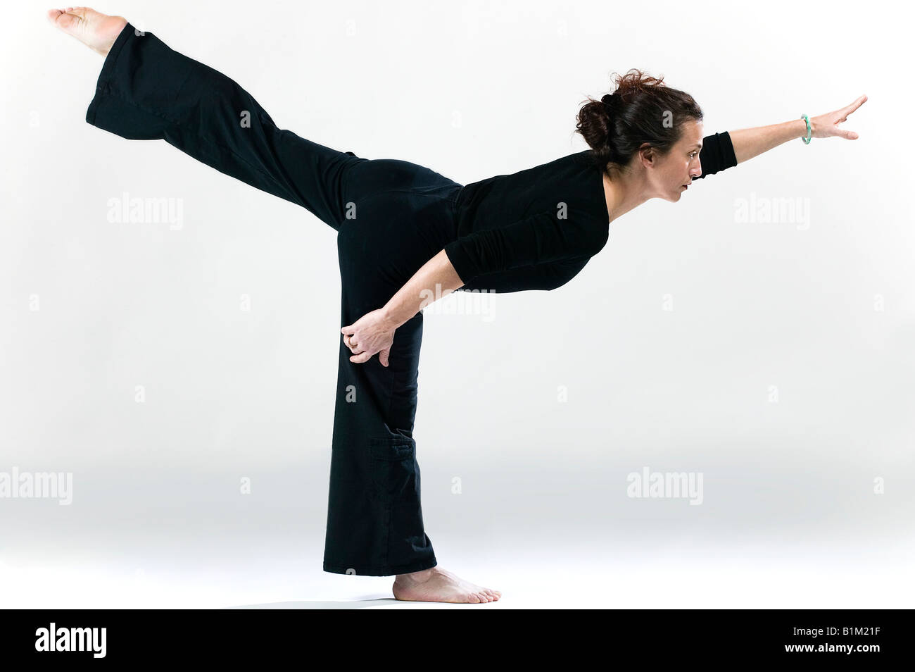 profile view of a woman practicing yoga one leg pose Stock Photo - Alamy