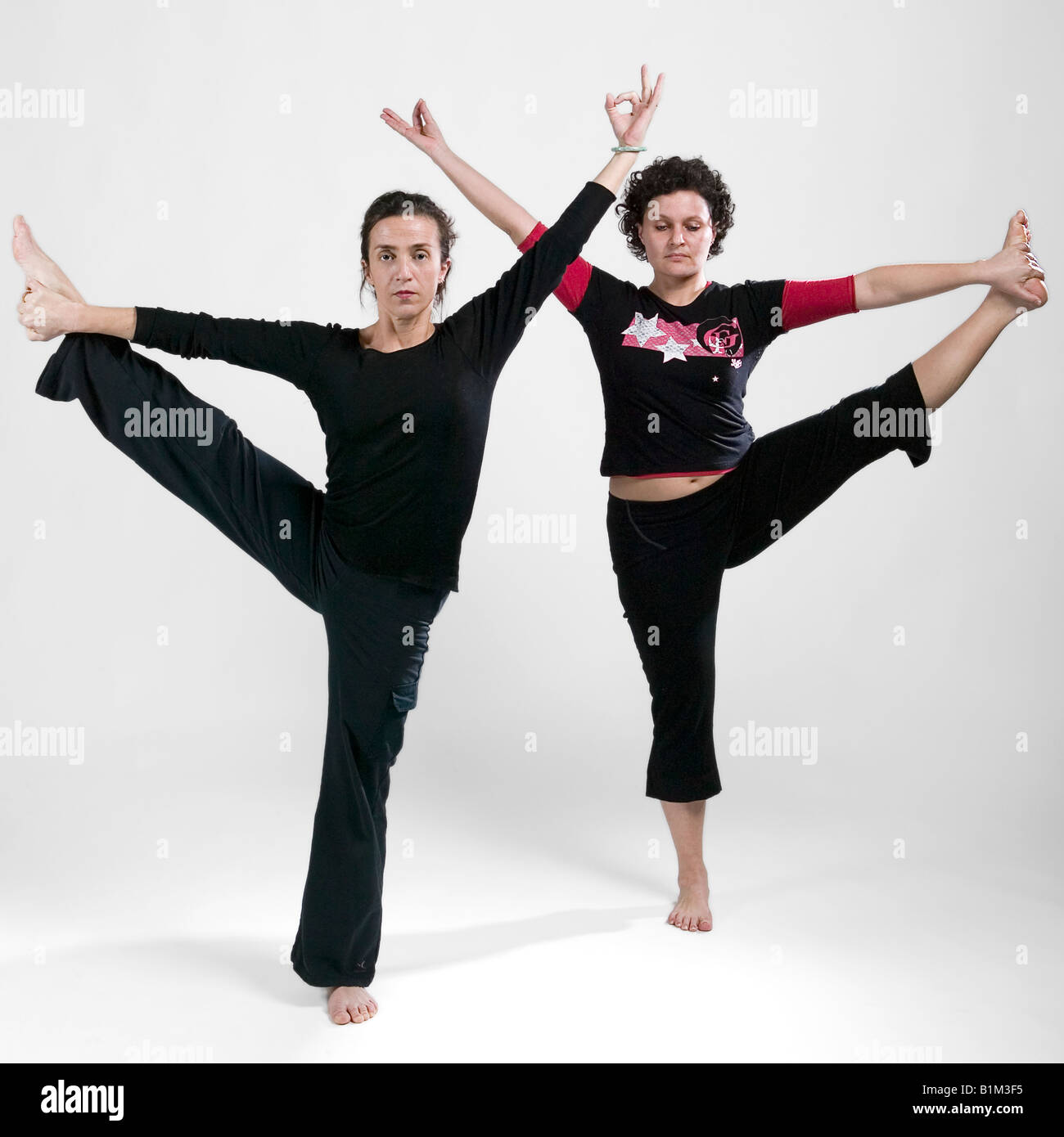 frontal view of two women side by side in a standing balancing pose ...
