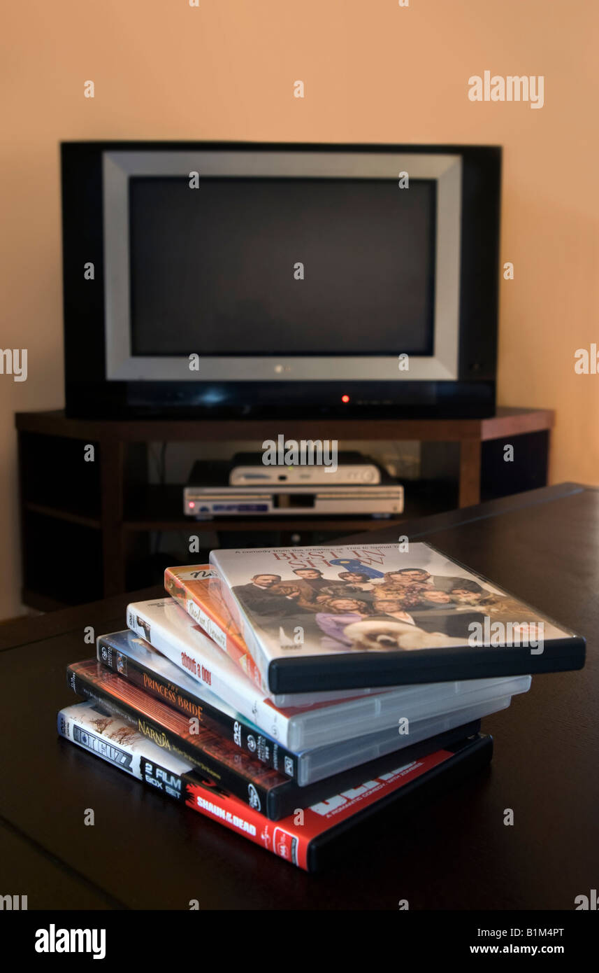 A pile of DVD movies with a television and DVD player in the background ...