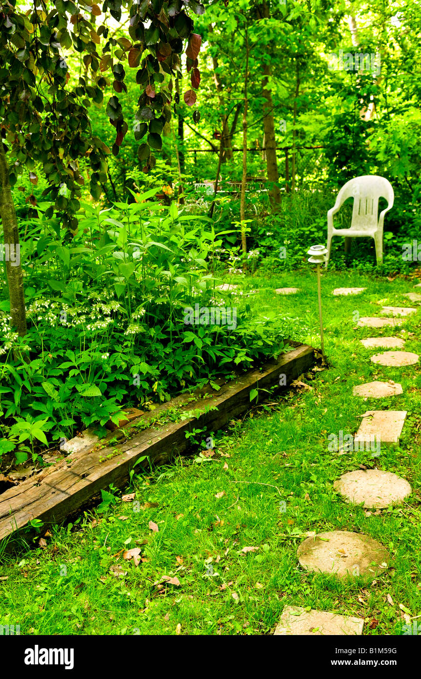 Path of stepping stones leading to secluded corner in lush green garden ...