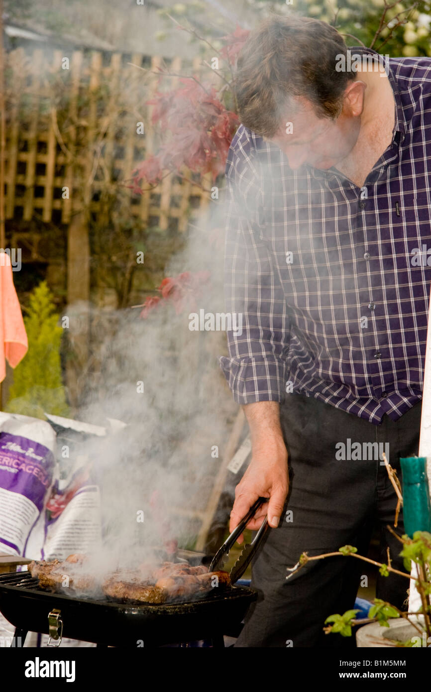 Mature man cooking meat on a smoking barbecue Stock Photo - Alamy