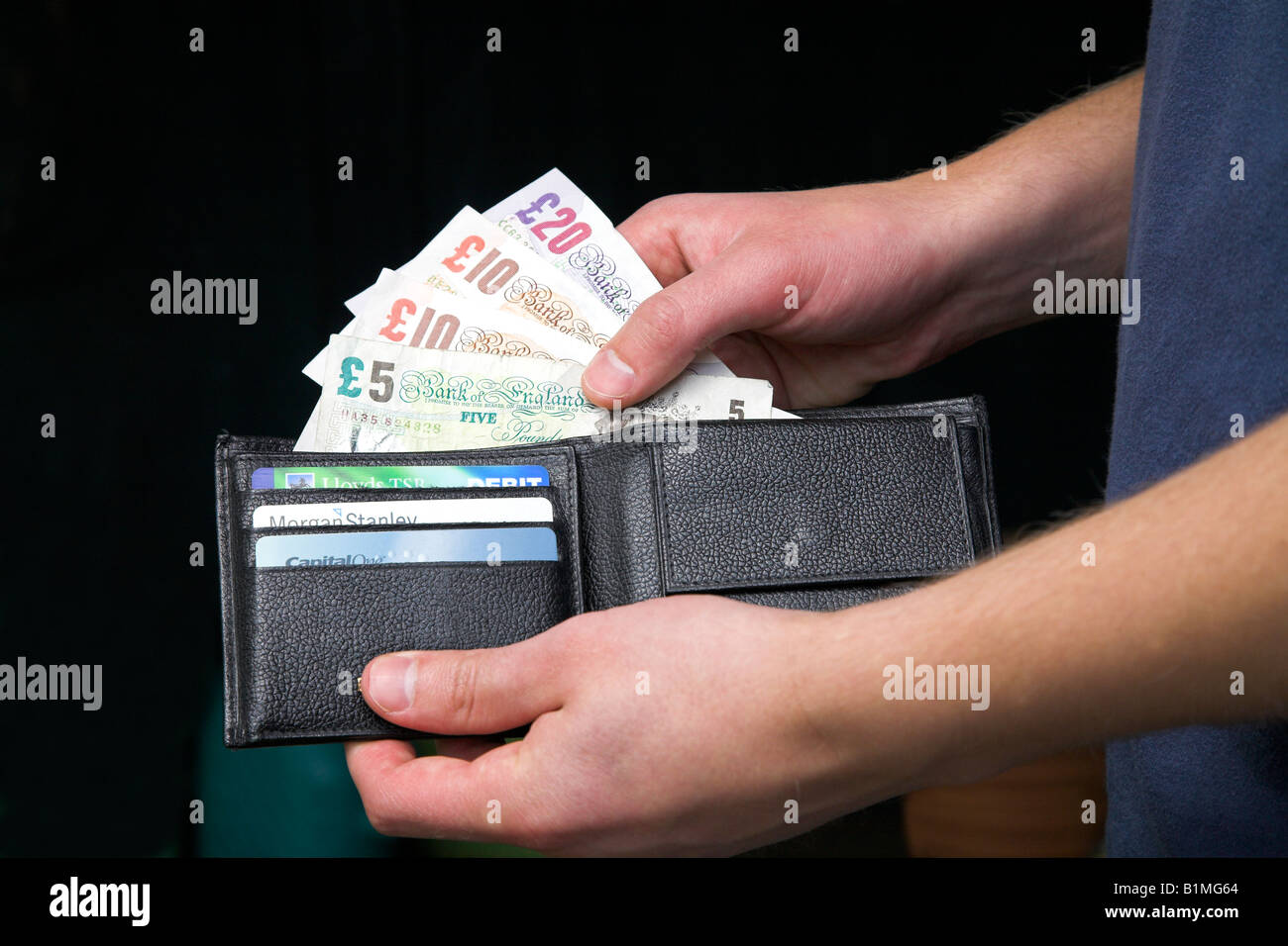 Wallet containing sterling pound notes isolated on black background ...