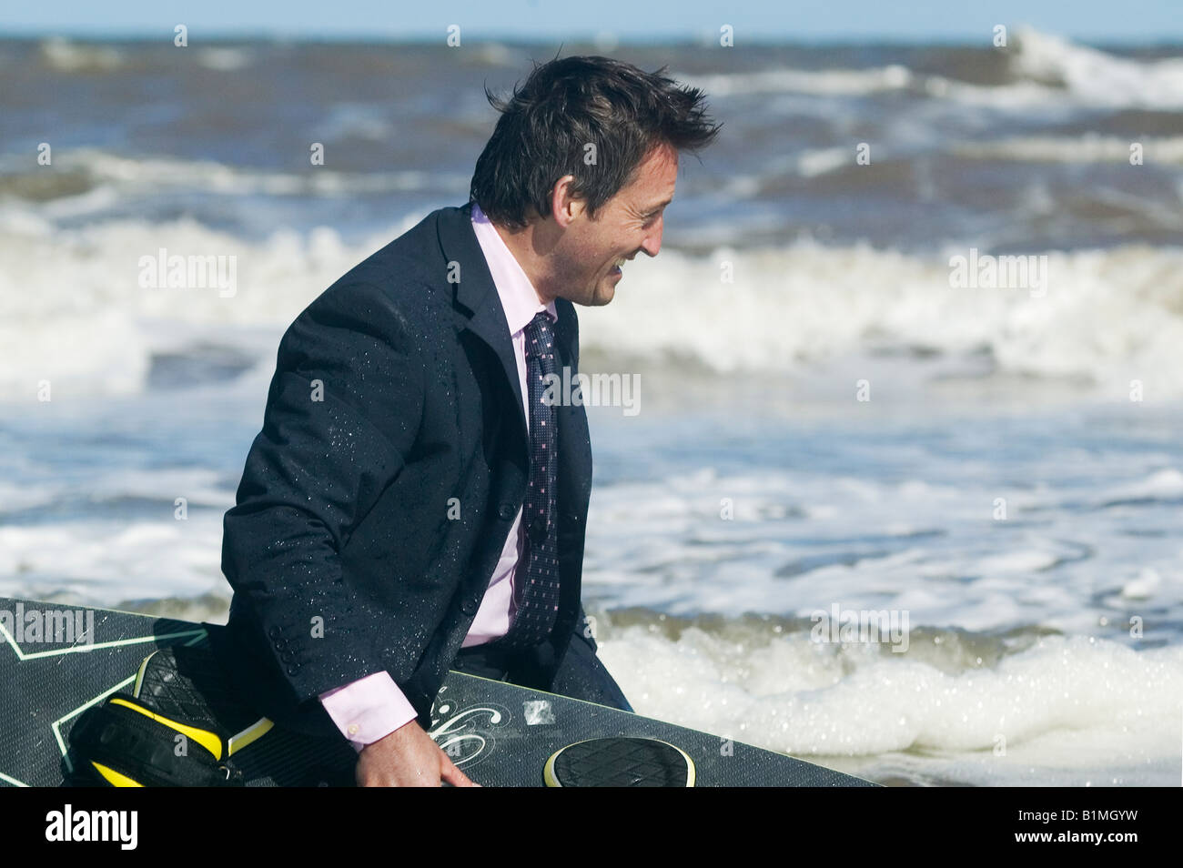 a business man in a suit getting into the water to surf Stock Photo - Alamy