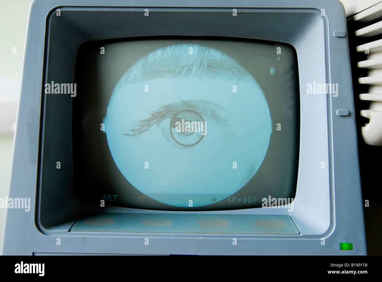 Female eye looks out from a black and white monitor during an eye test ...