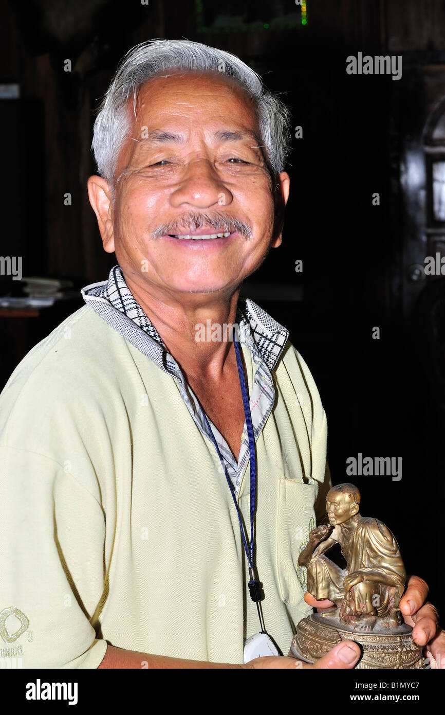 Asian man proudly showing one of his Buddha statues Stock Photo - Alamy