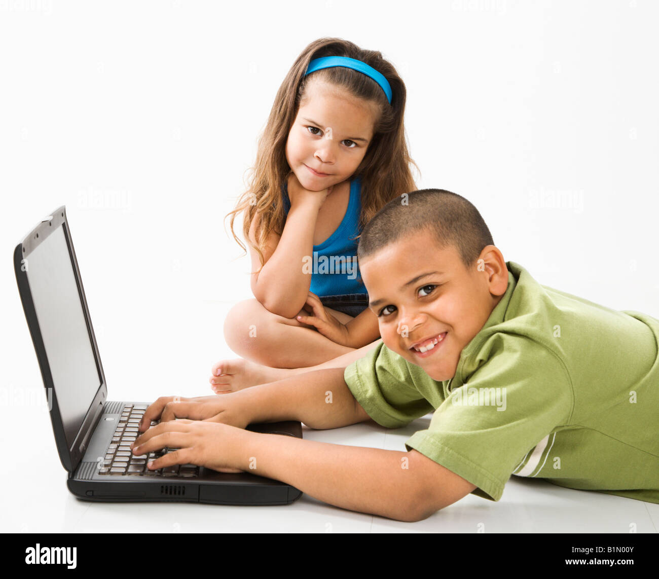 Young latino boy using laptop computer while girl watches Stock Photo ...