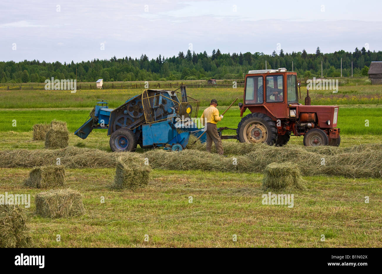 Farmers bailing the hay crop using old style equipment Stock Photo - Alamy