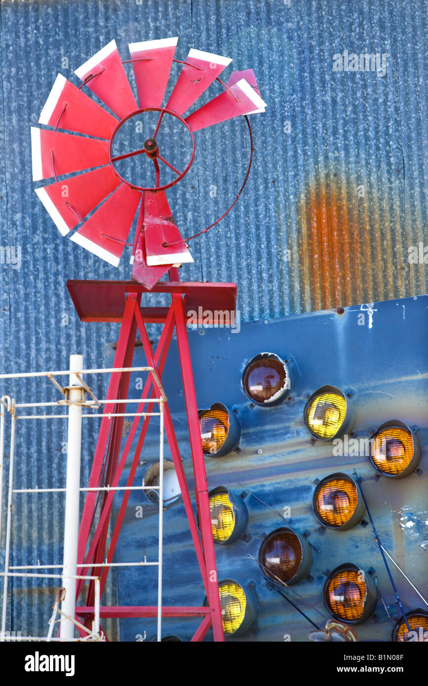 Broken red windmill against rusted blue corrugated metal building ...