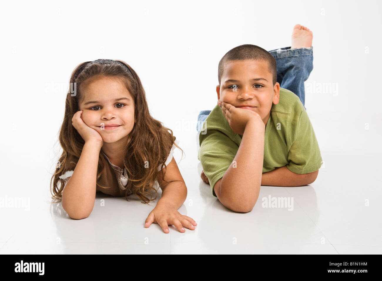 Portrait of Hispanic brother and sister lying on floor smiling at ...
