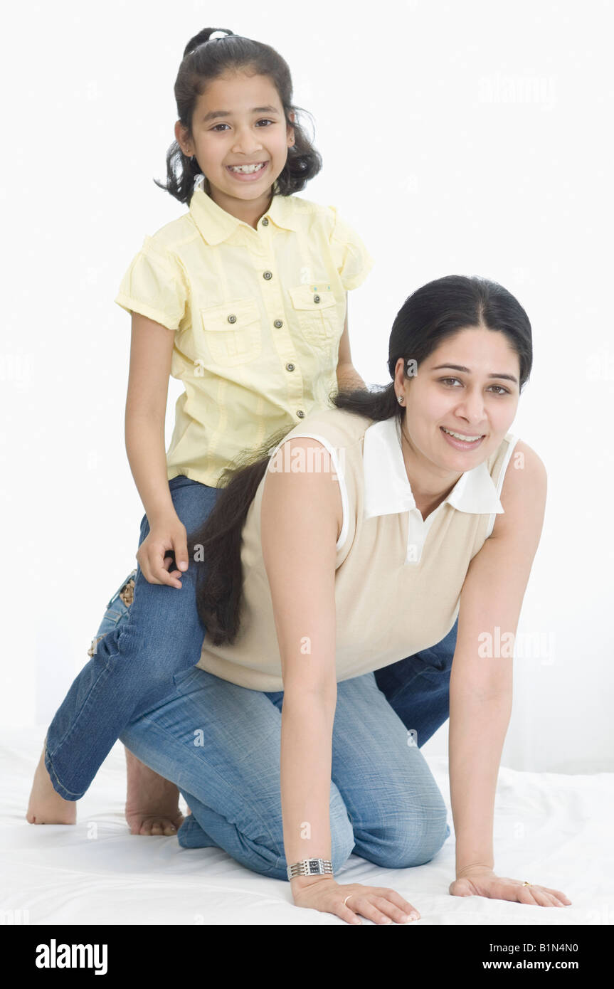 Portrait of a girl sitting on her mother's back and smiling Stock Photo ...