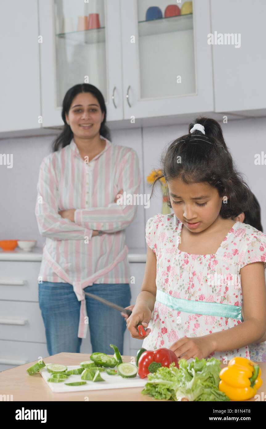 Close-up of a girl cutting vegetables on a cutting board with her ...