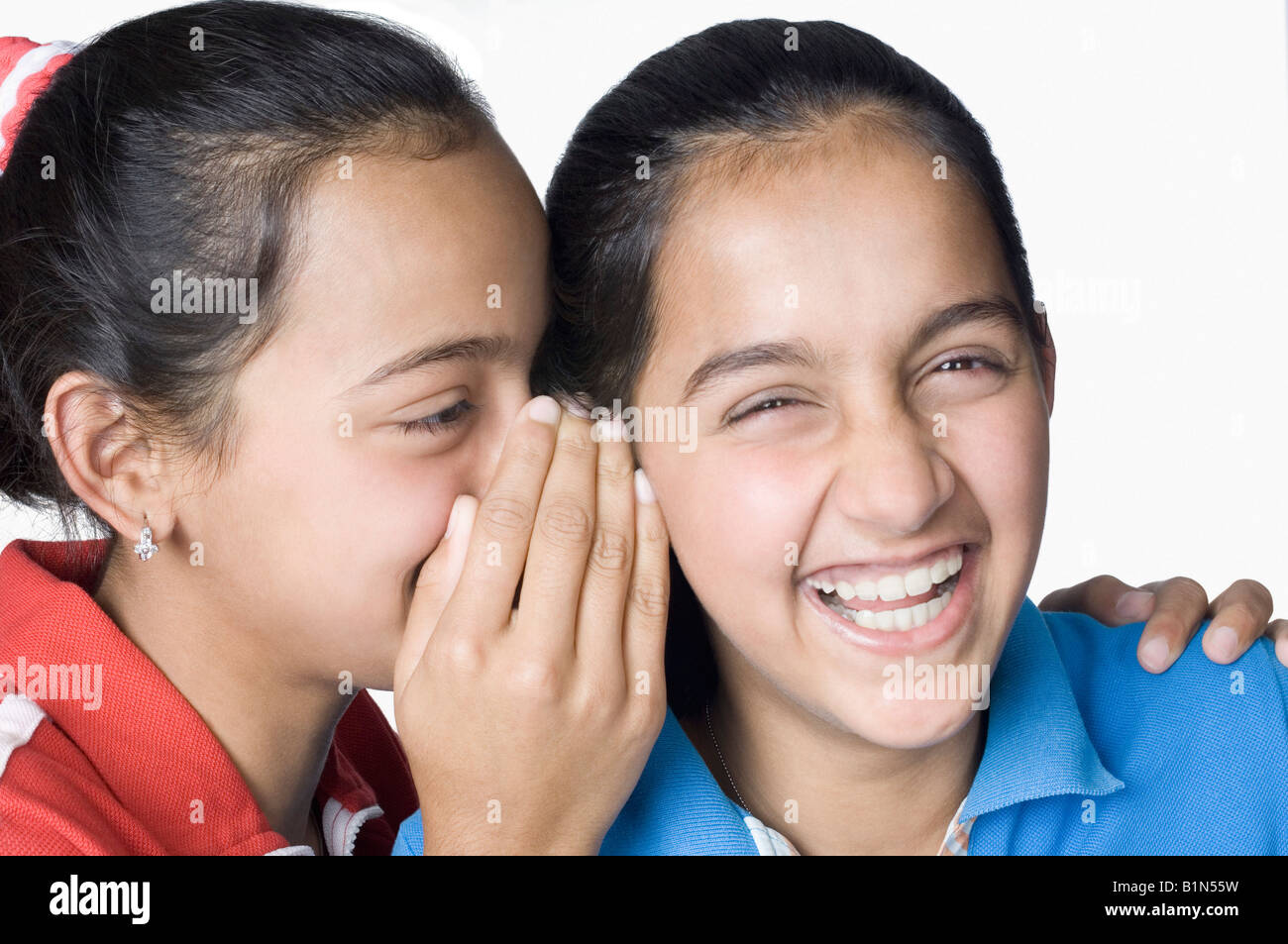 Girl whispering into her sister's ear Stock Photo - Alamy