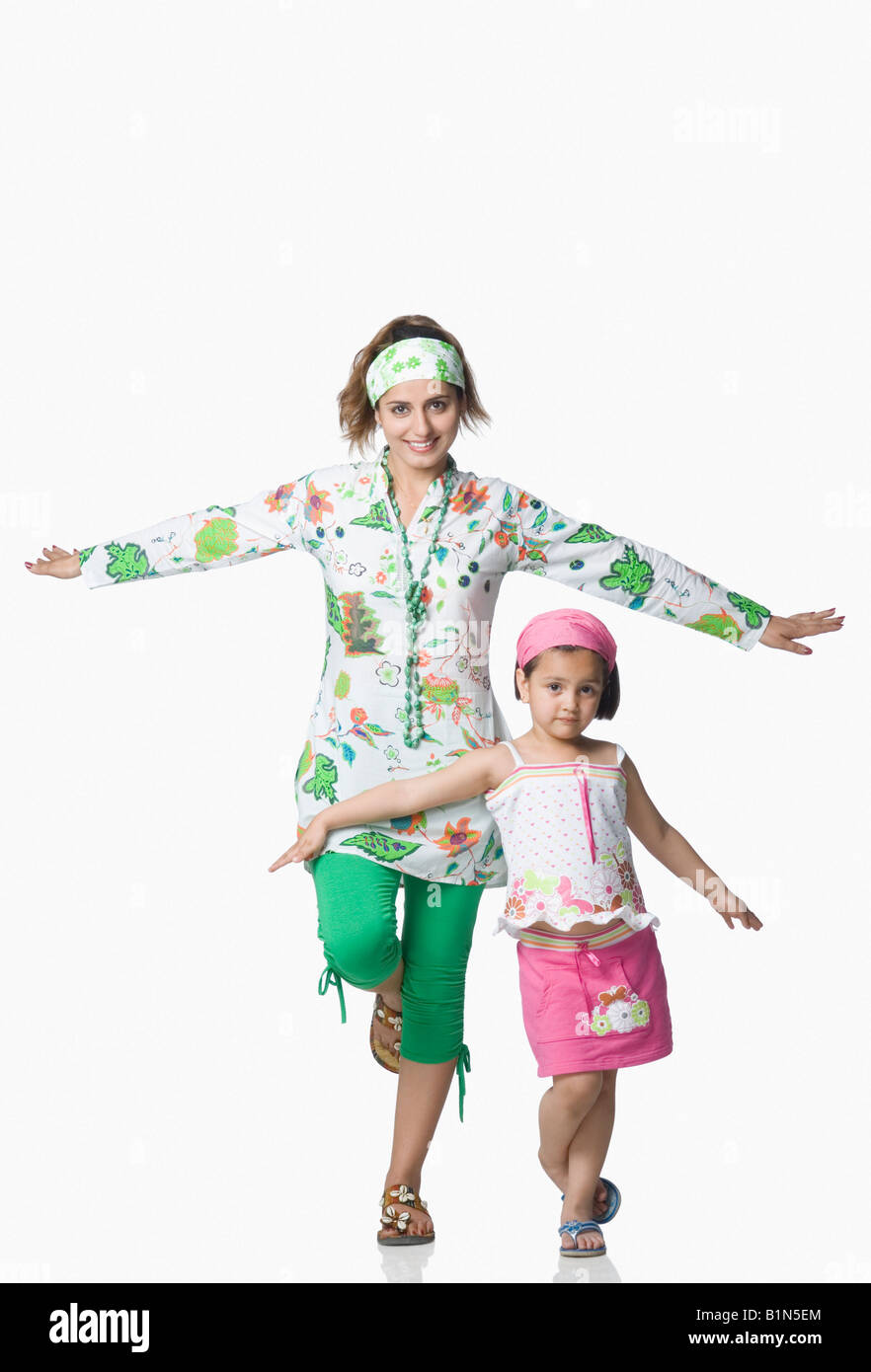 Portrait of a young woman and her daughter standing with their arms ...
