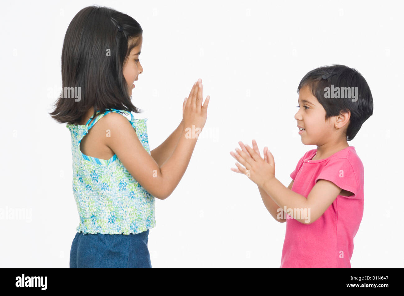 Side profile of two girls playing patty cake and smiling Stock Photo ...