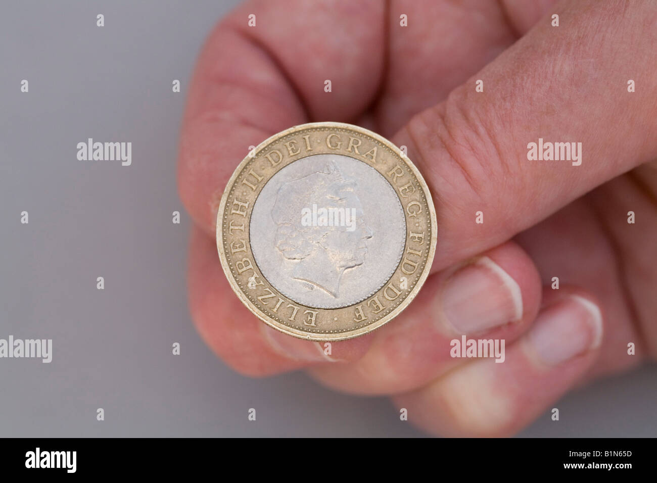 Studio Still Life Close up Hand about to spin a 2 coin heads side up ...