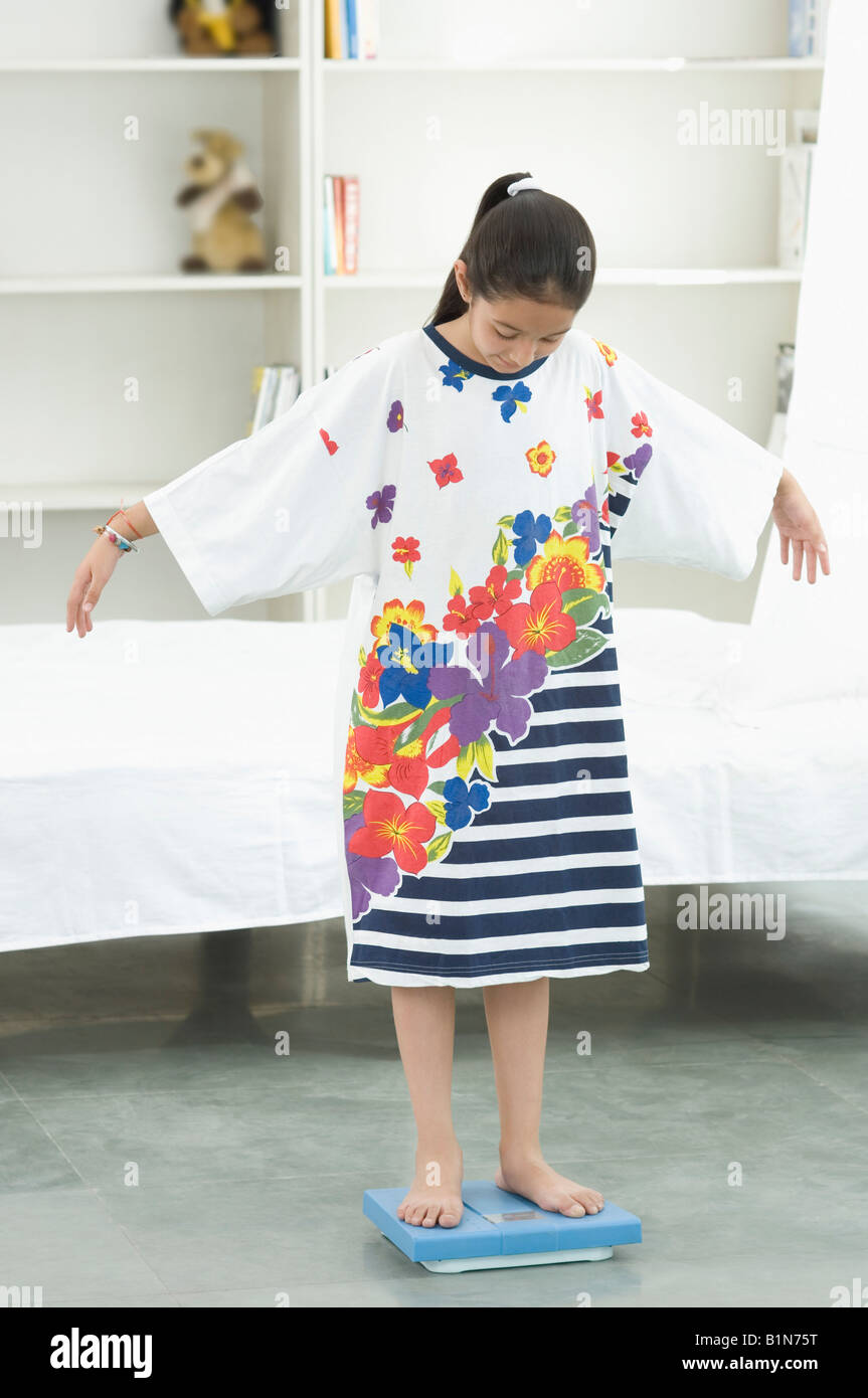 Girl standing on a weighing scale Stock Photo - Alamy