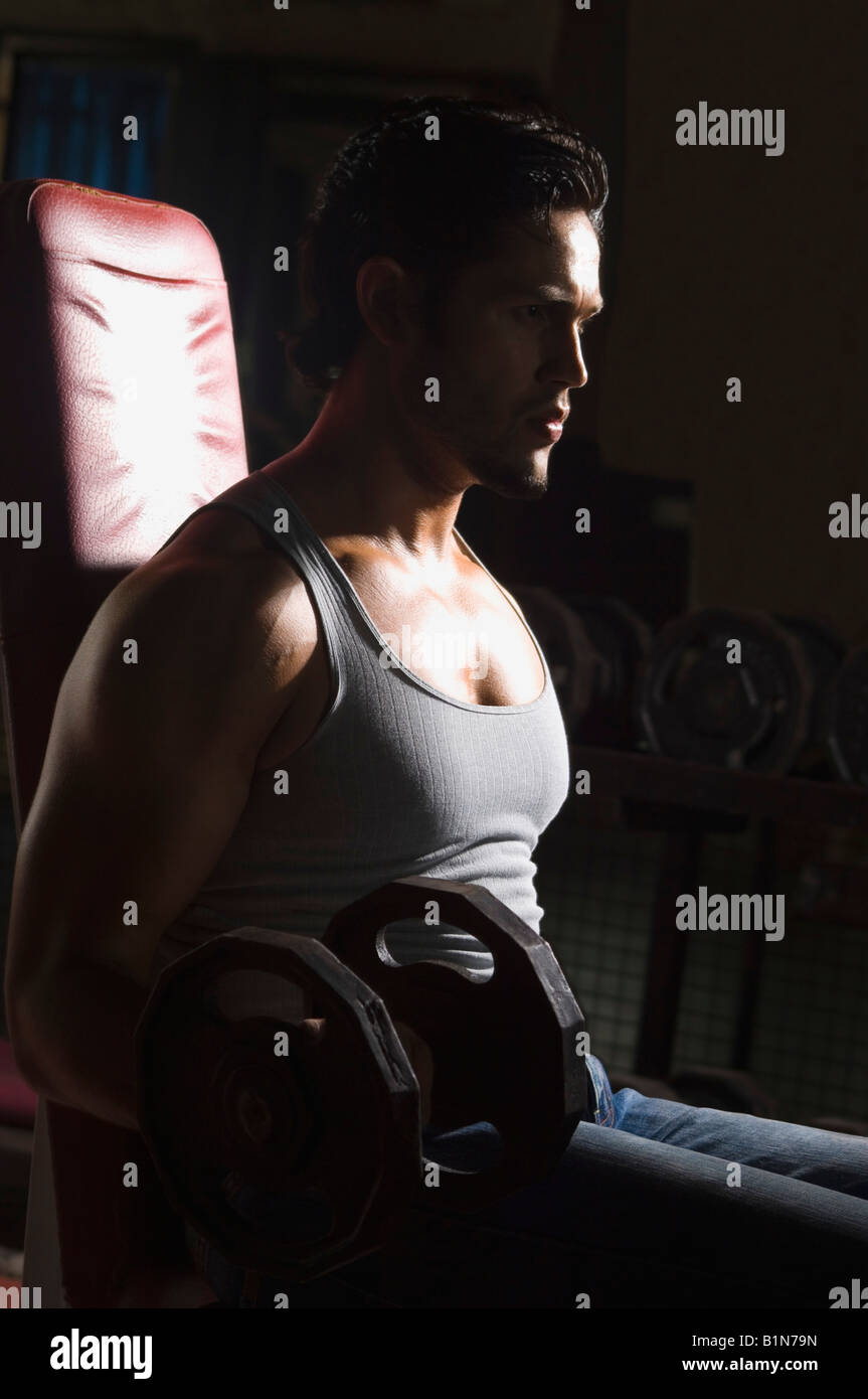 Side profile of a young man exercising with dumbbells in a gym Stock ...